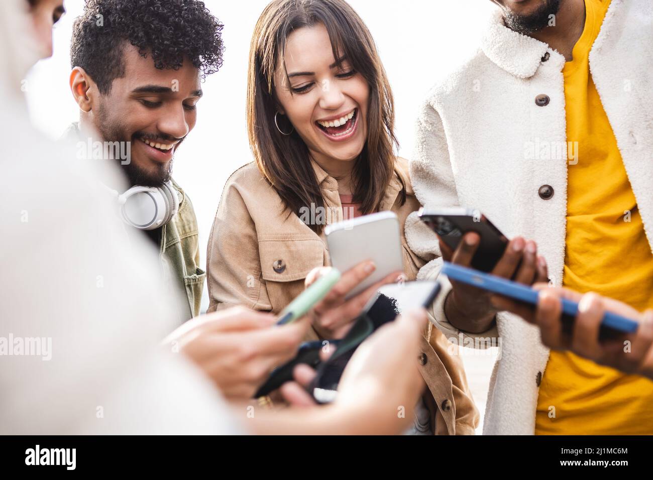 Young group of people laughing using mobile phone outdoors Stock Photo ...