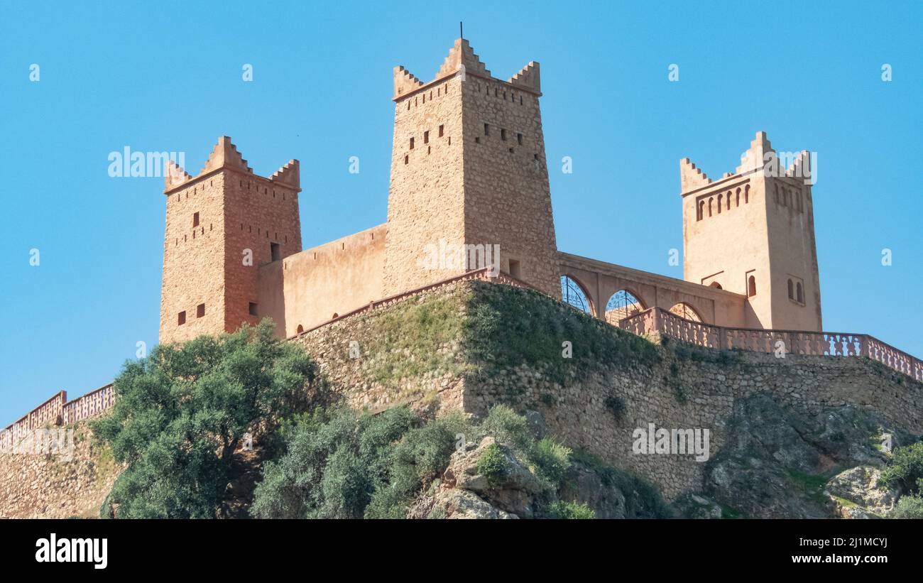 A light coloured stone castle on the top of a hill with turrets and ...