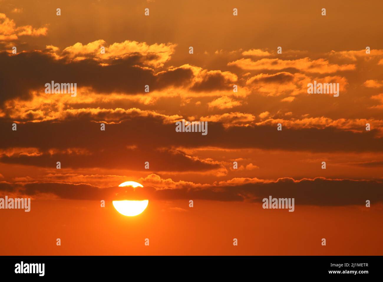 View of a colourful sunset on a March evening with the sun peeking out ...