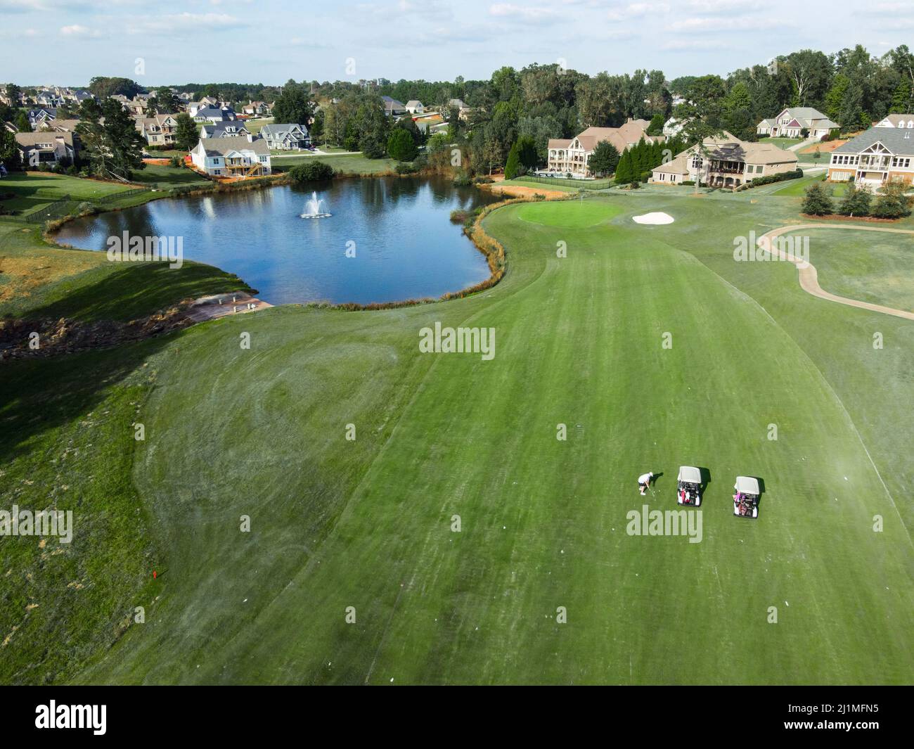 An aerial view of golf course with golf carts by the lake Stock Photo ...