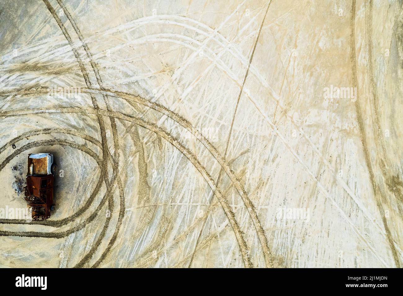 Rusted car wreck left to disintegrate on a dry lake bed salt flat with ...