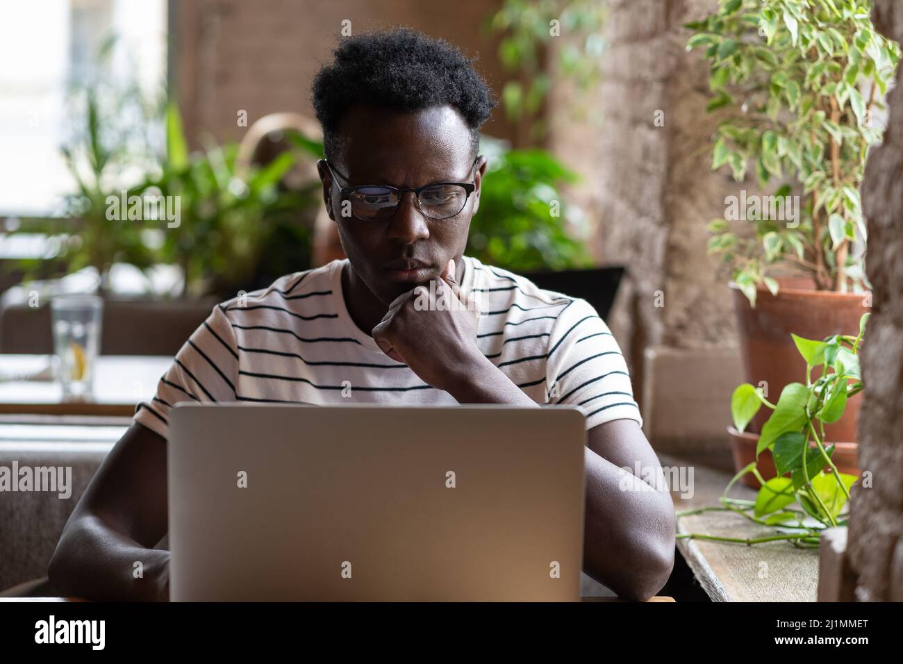 Thoughtful Black man watching educational webinar on laptop, studying ...