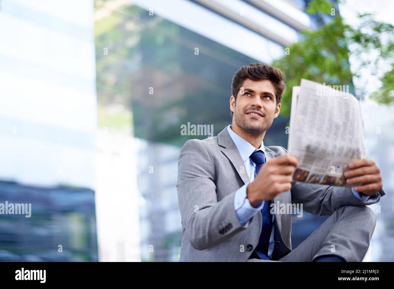 A quick break during a busy day. A handsome young businessman reading a ...