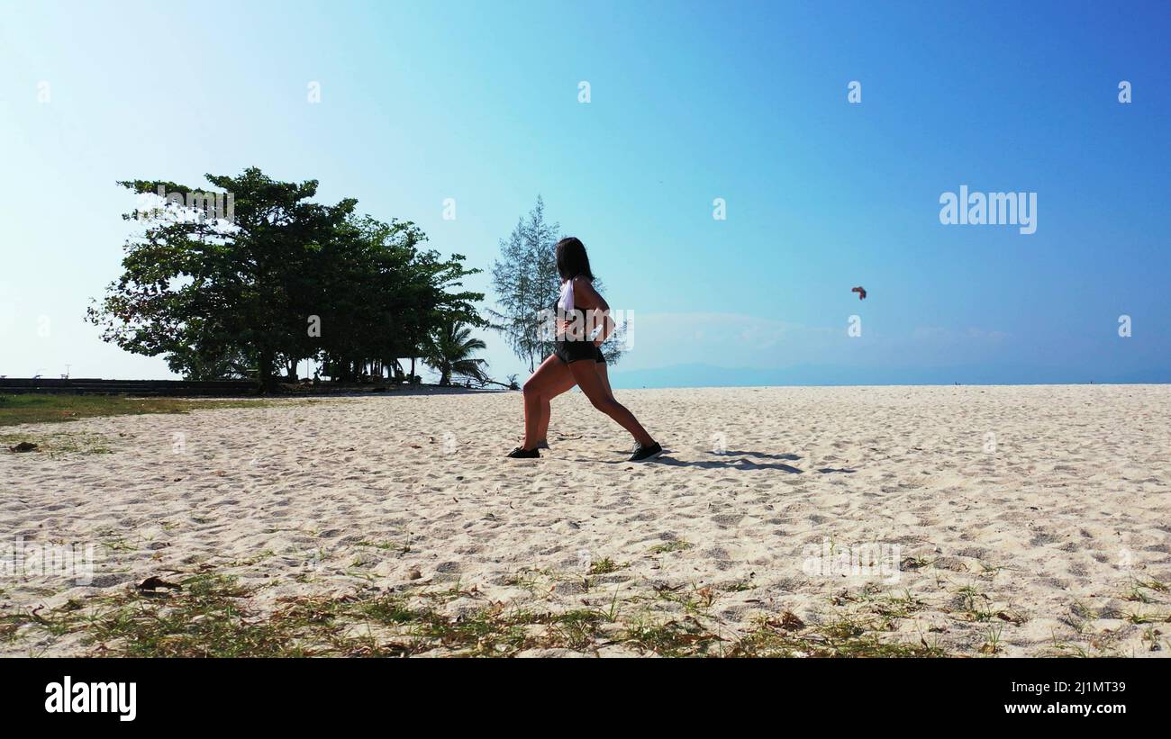 A Two Caucasian pretty females in gym outfit exercising on the sandy ...