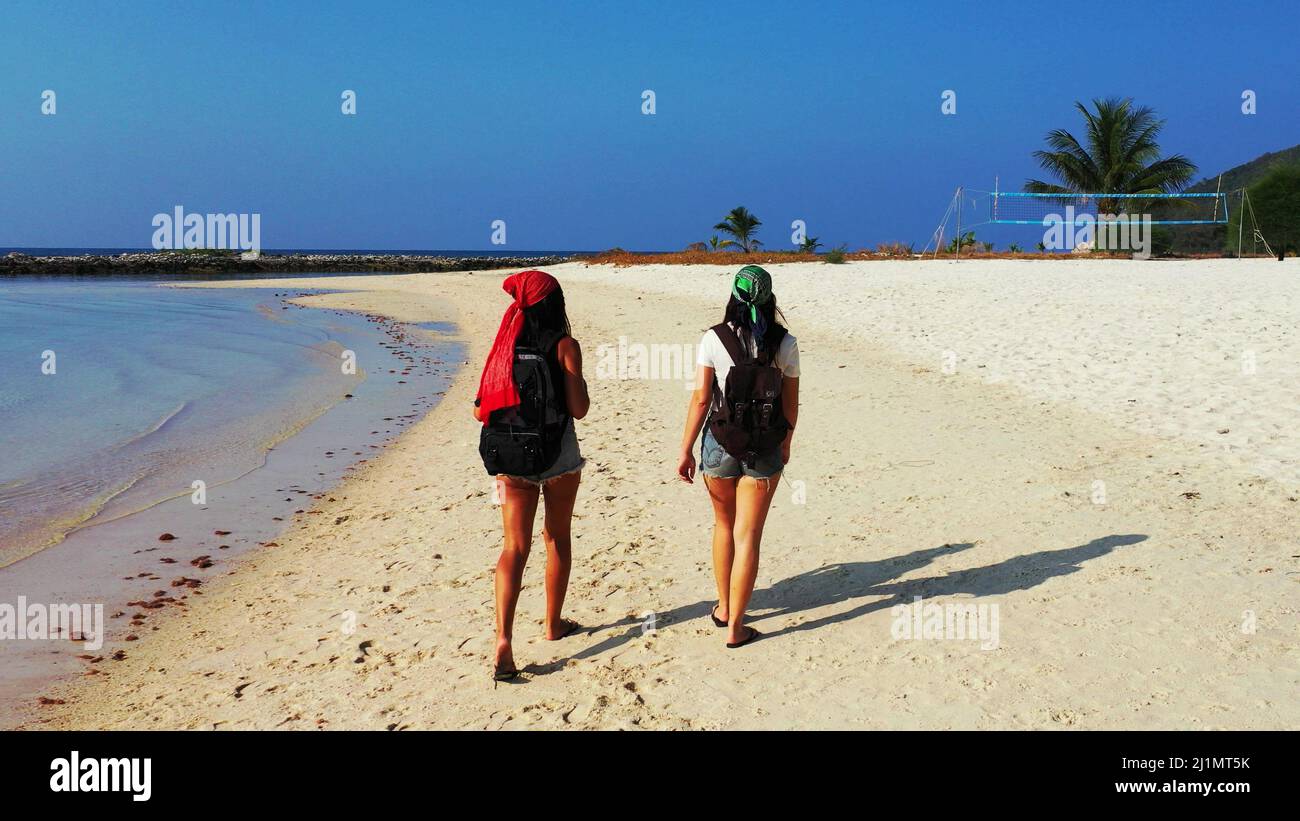 A backshot of two Caucasian females with backpacks walking on the ...