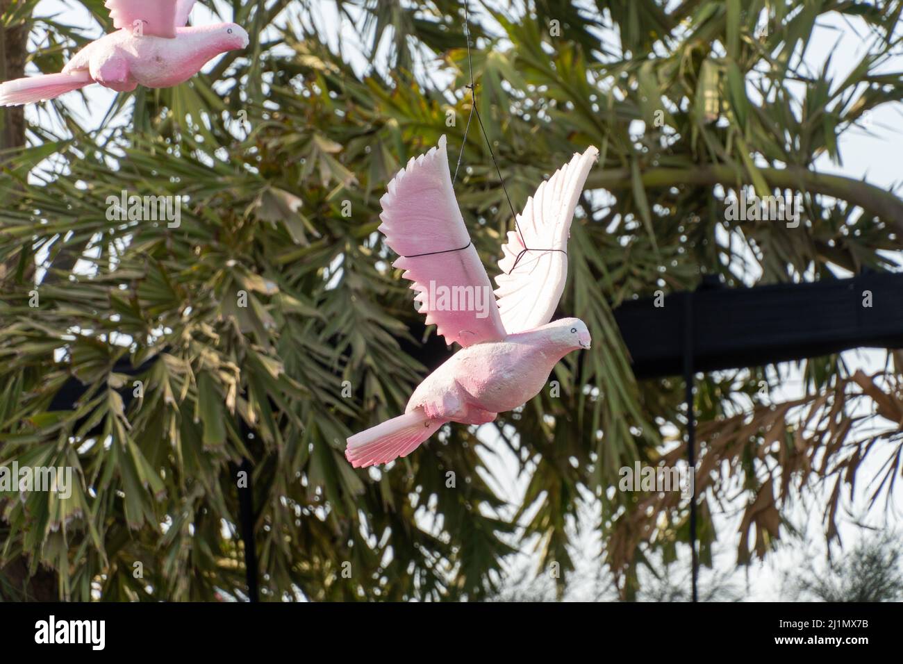 An artificial pink bird in flight hanging on a tree Stock Photo - Alamy