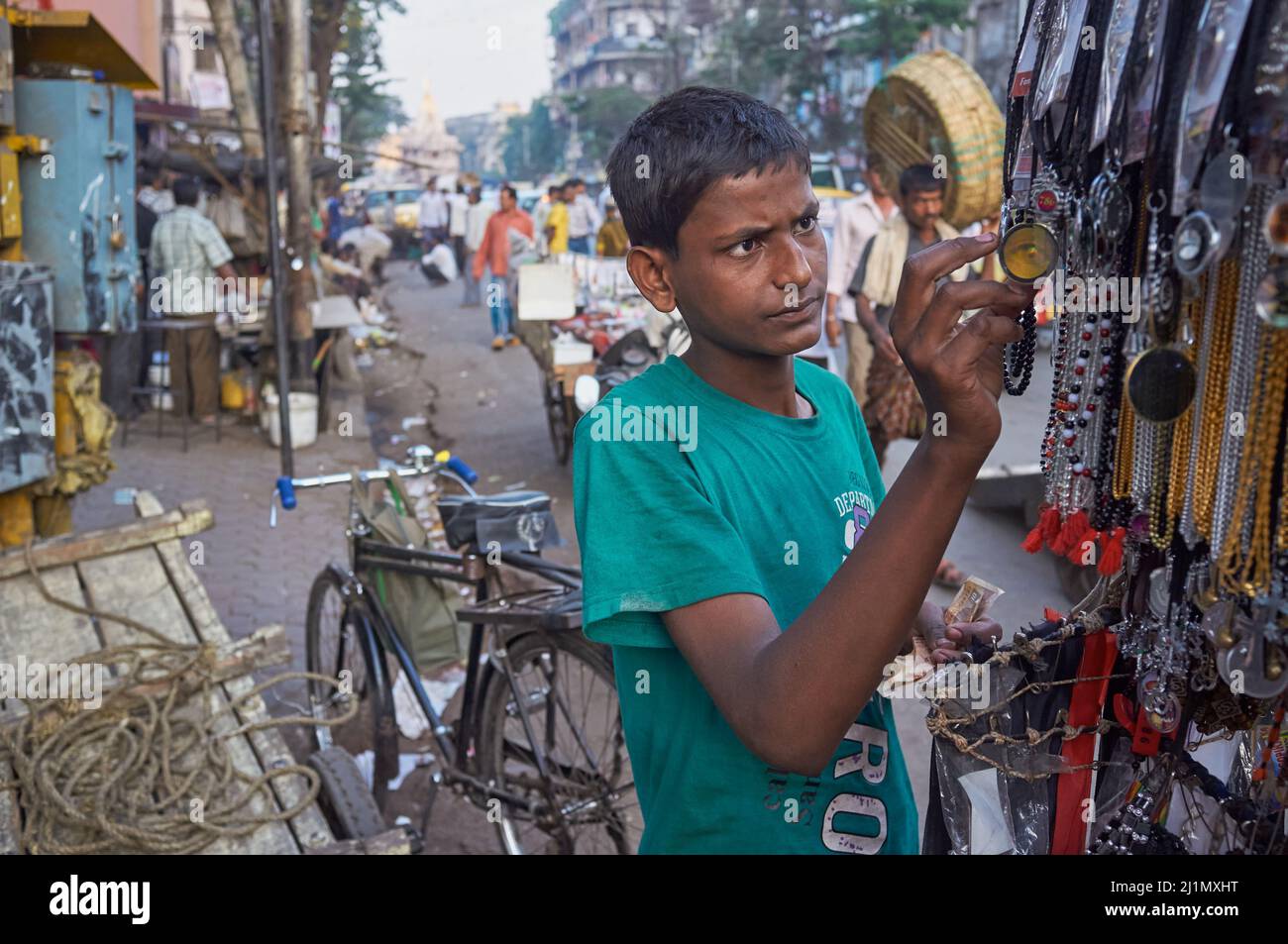 An Indian boy scrutinizes some bric-a-brac at a sales stall in bustling ...