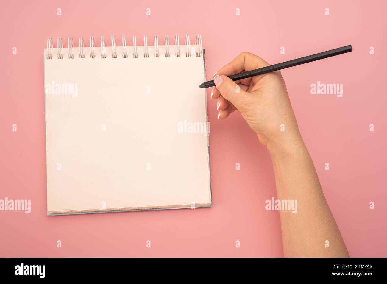 Mockup notepad. woman hand with pencil next to an empty blank white ...