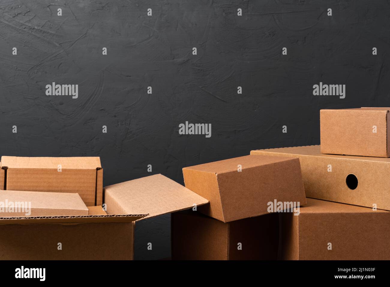 Stack of cardboard boxes against black background Stock Photo - Alamy