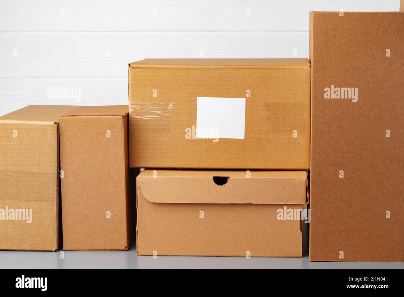 Group of cardboard boxes against white wooden wall Stock Photo - Alamy