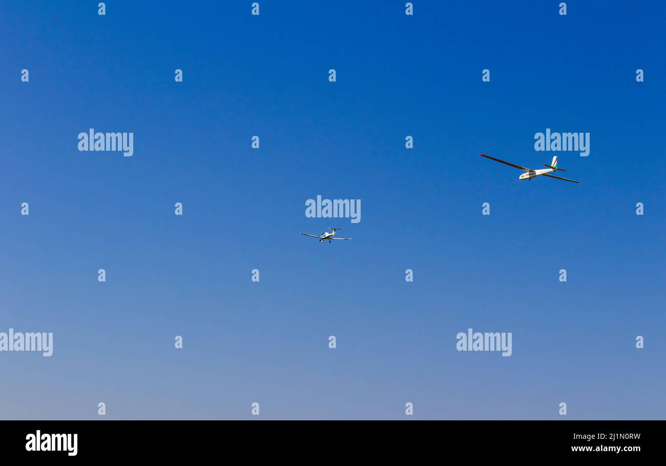 Ultra light, cessna plane drag on glider with prolonge rope on blue sky ...