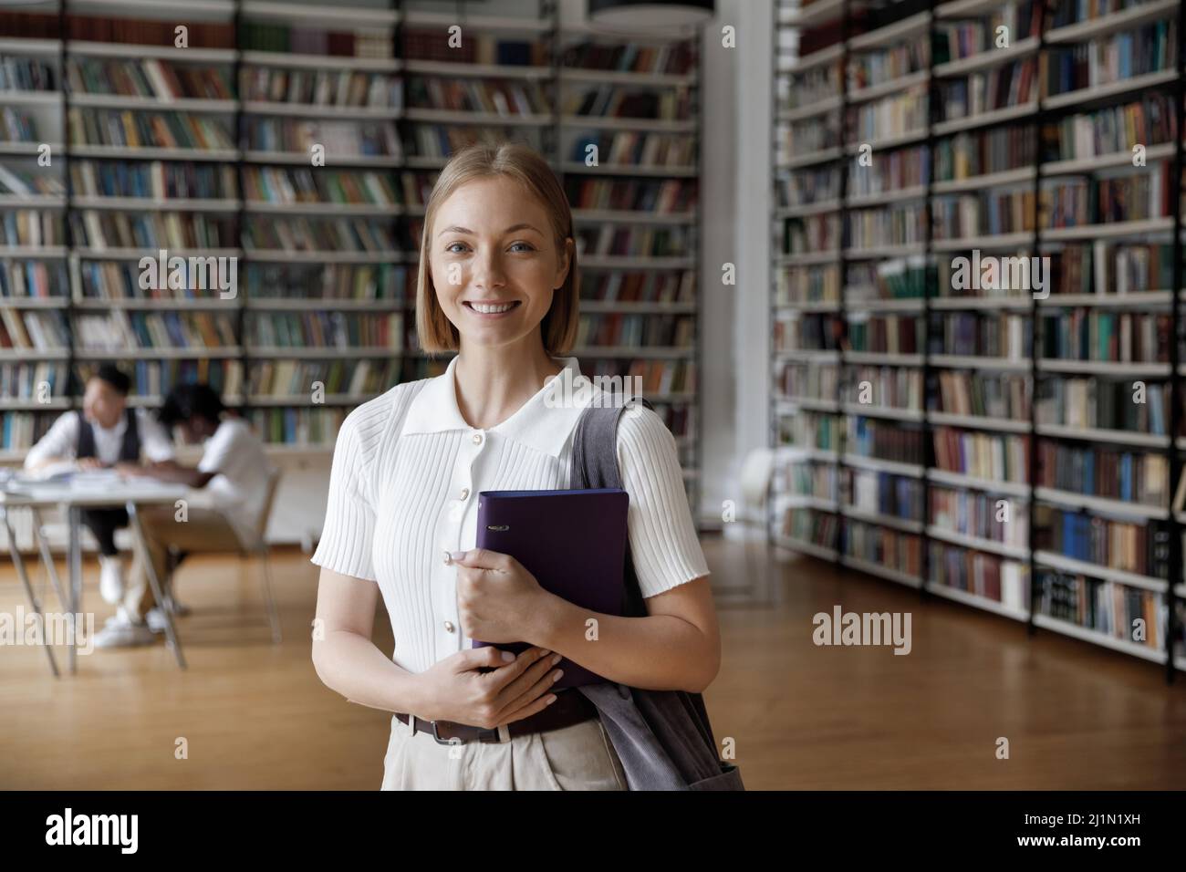Beautiful smiling blonde teen girl posing in university library Stock ...
