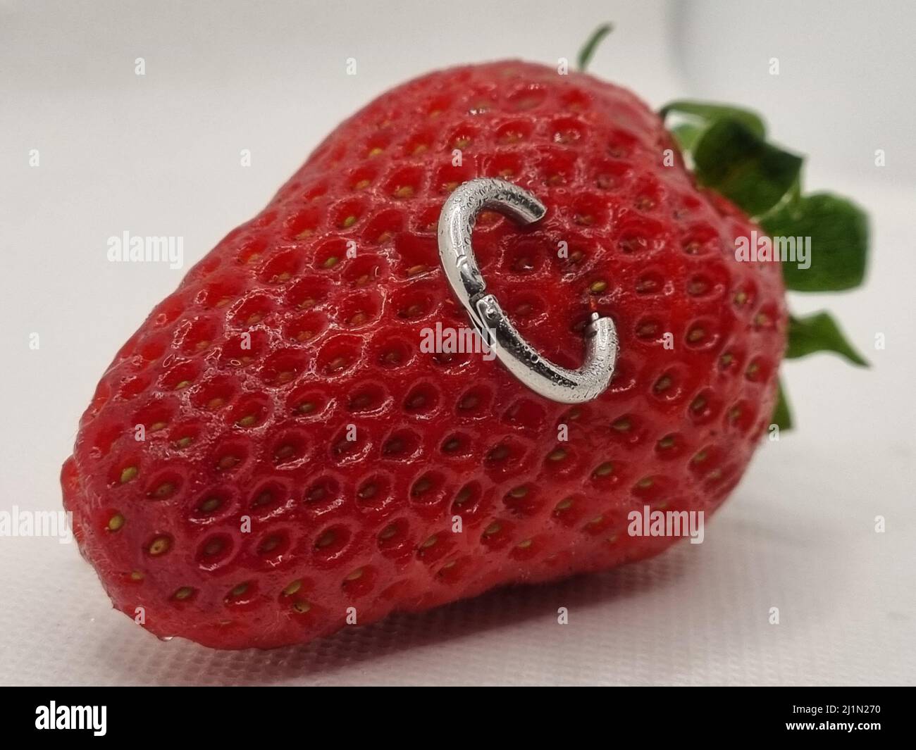 A closeup of a strawberry with a ring thrust in it isolated on a white ...