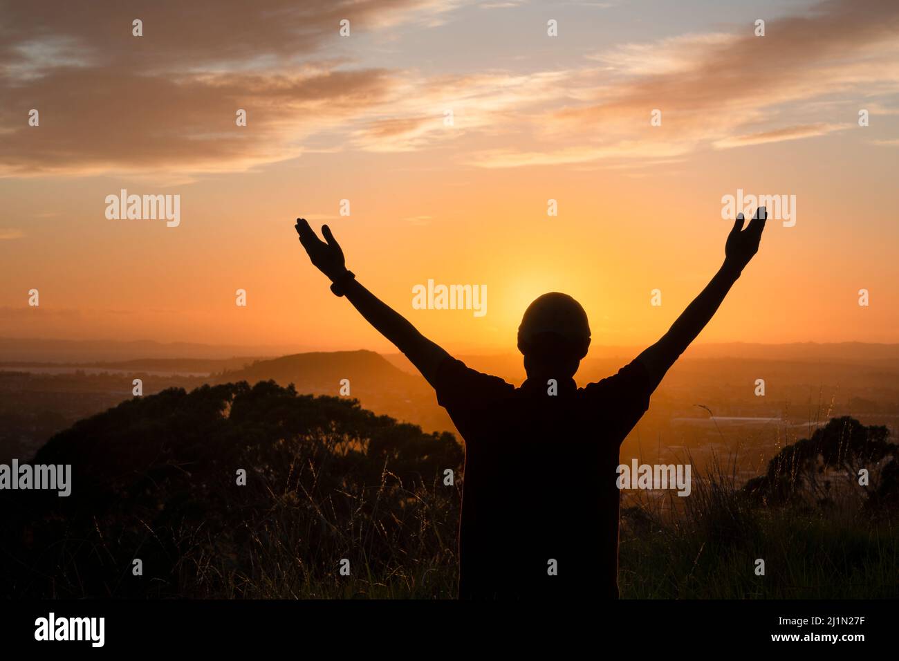 Silhouette of a man with open arms greeting the sun rising over ...