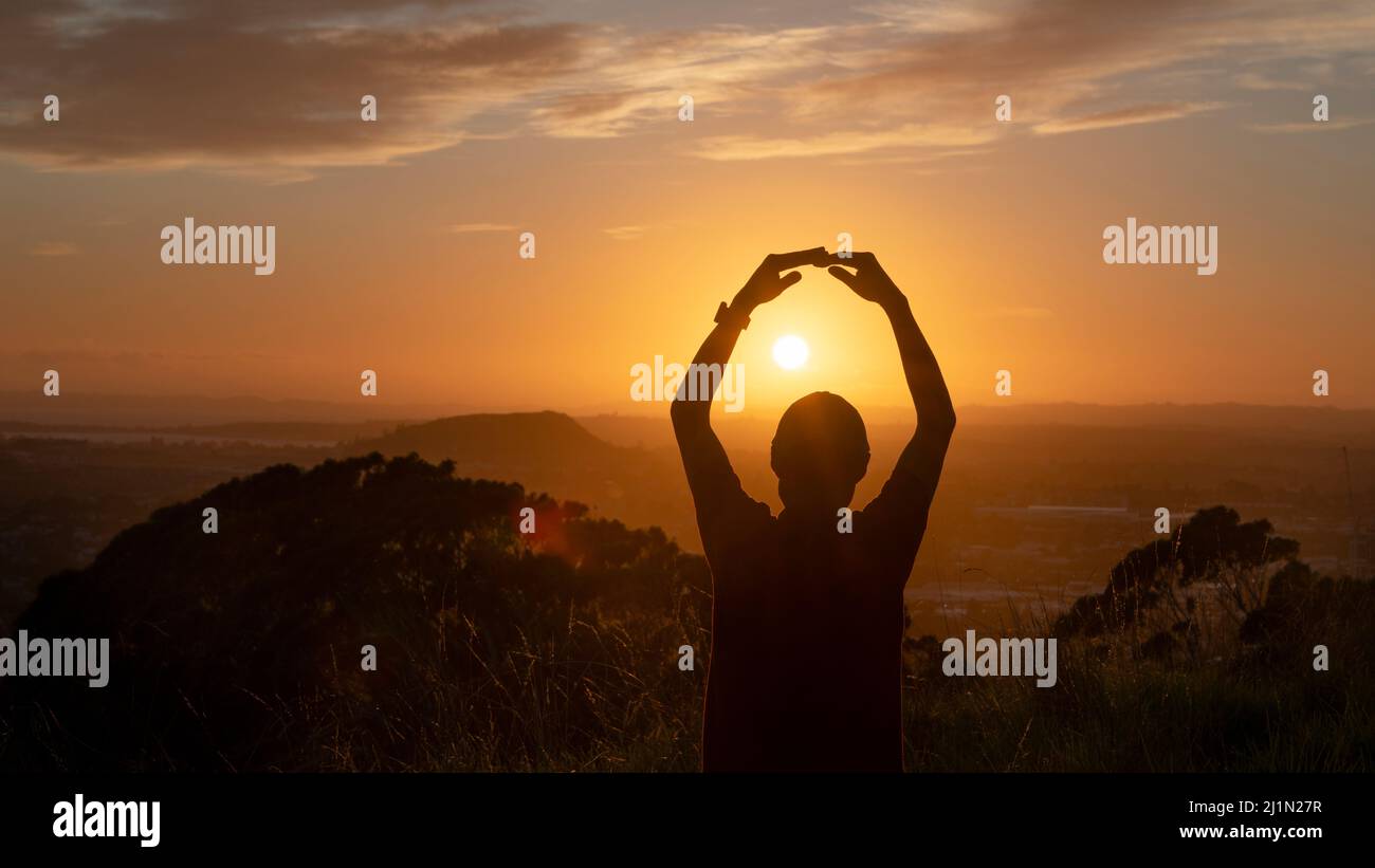 Silhouette of a man raising arms embracing the sun Stock Photo - Alamy