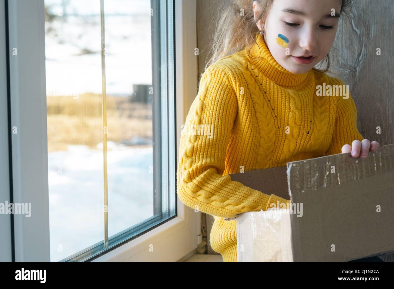 A child on the window with a humanitarian aid box with the flag of ...