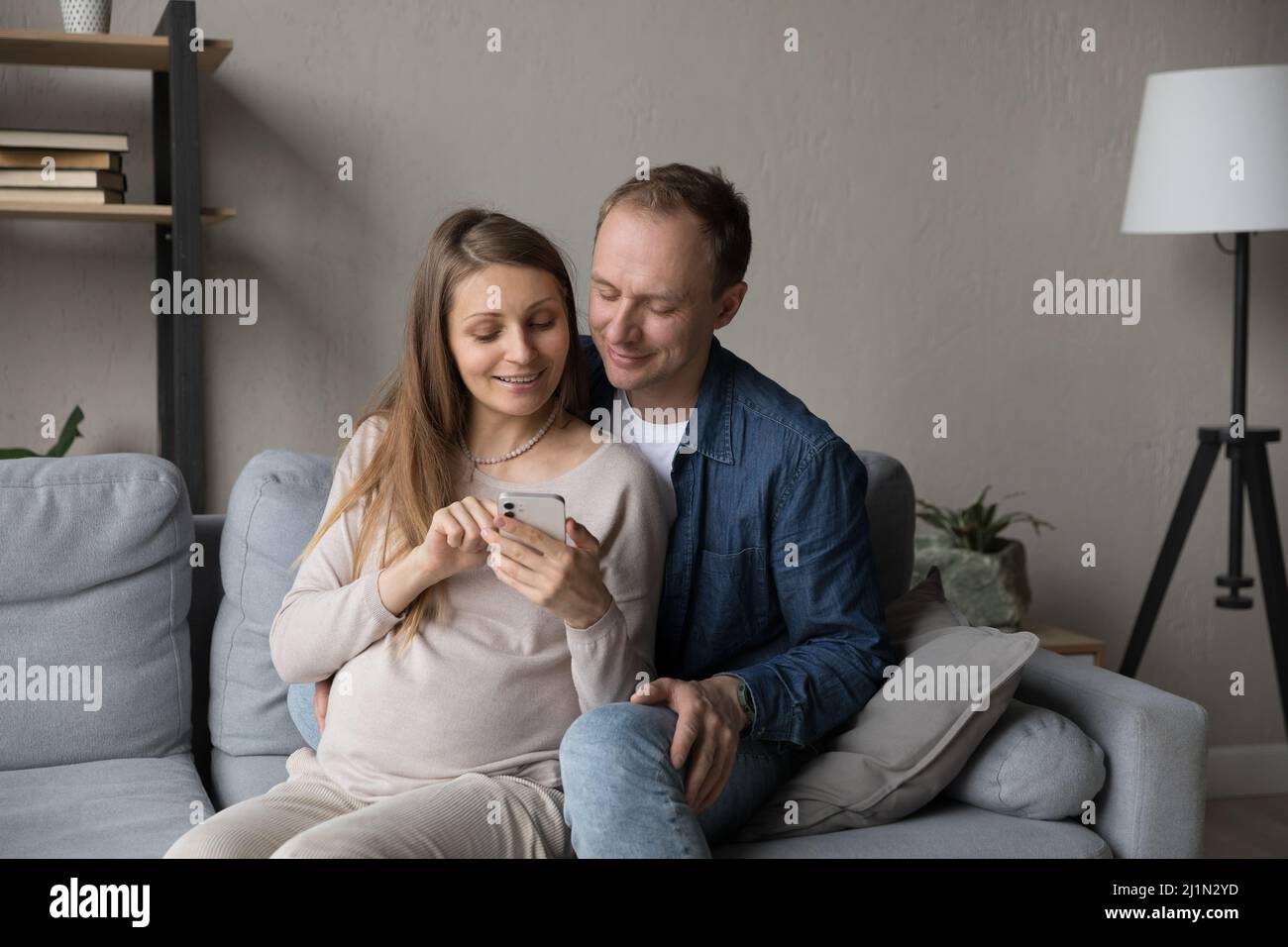 Happy young future parents using cellphone at home Stock Photo - Alamy
