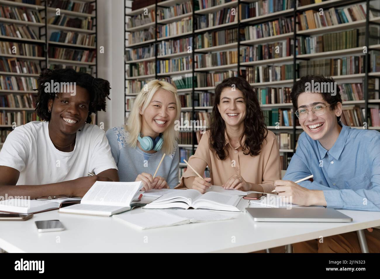 Portrait of four multi ethnic students studying in library Stock Photo ...