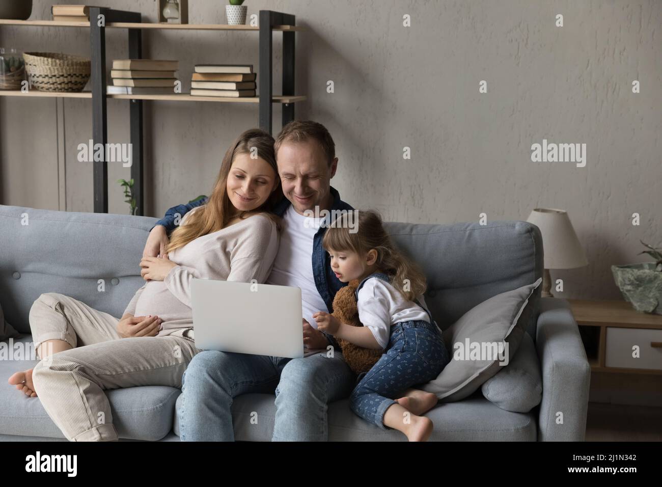 Happy young bonding couple parents using computer with daughter Stock ...
