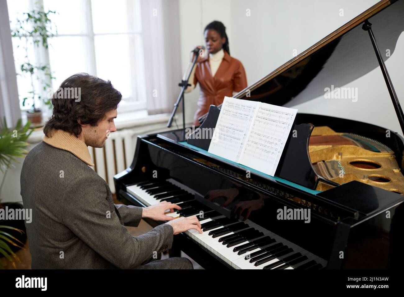 Young pianist sitting in front of the sheet music and playing the music ...