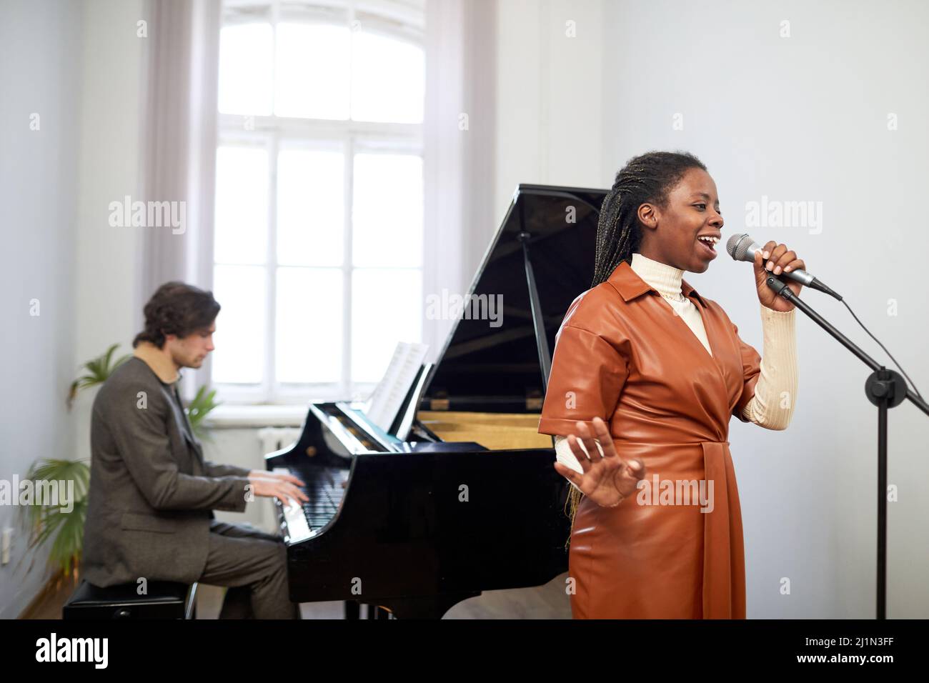 African woman in elegant leather dress standing and singing a song to ...