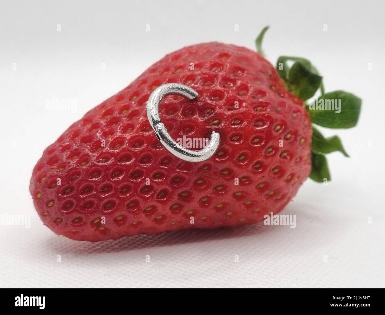 A closeup of a strawberry with a ring thrust in it isolated on a white ...