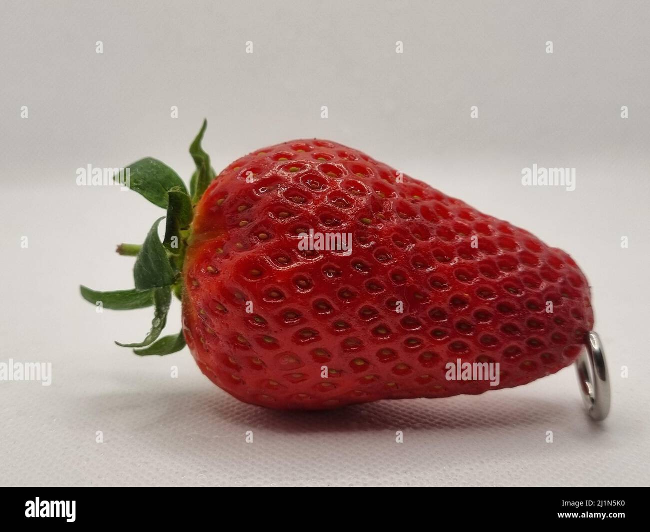 A closeup of a strawberry with a ring thrust in it isolated on a white ...