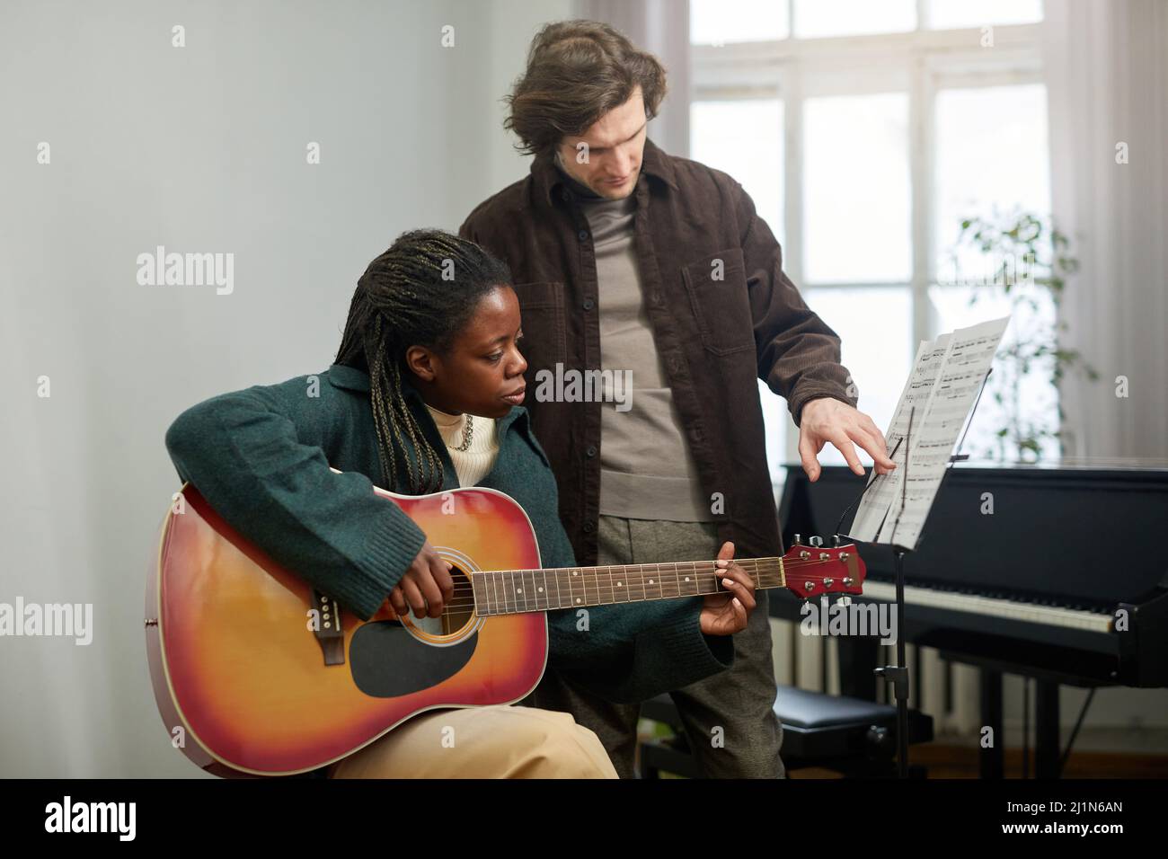 Teacher pointing at sheet music while his student learning to play the ...