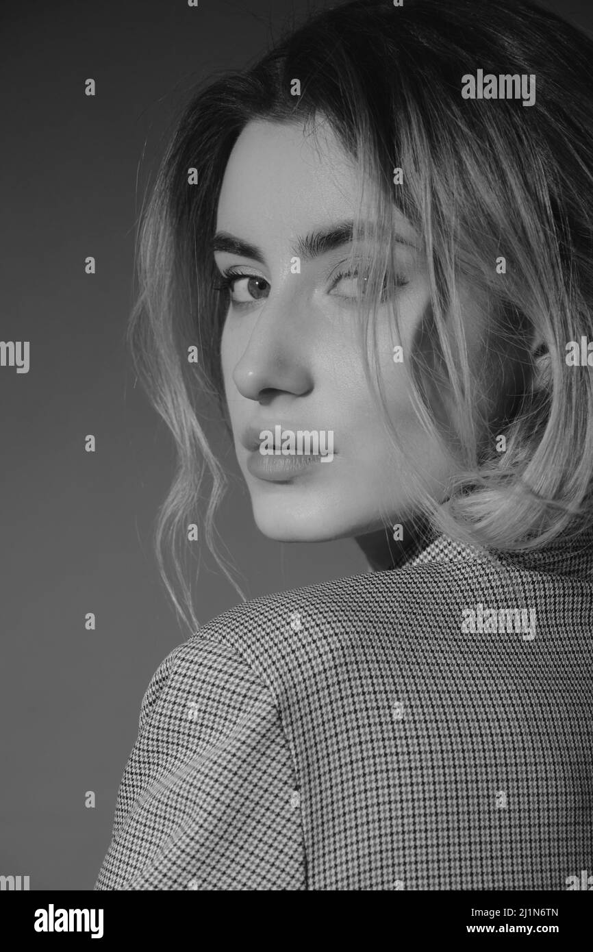 serious young woman in grey suit looking back over shoulder closeup ...