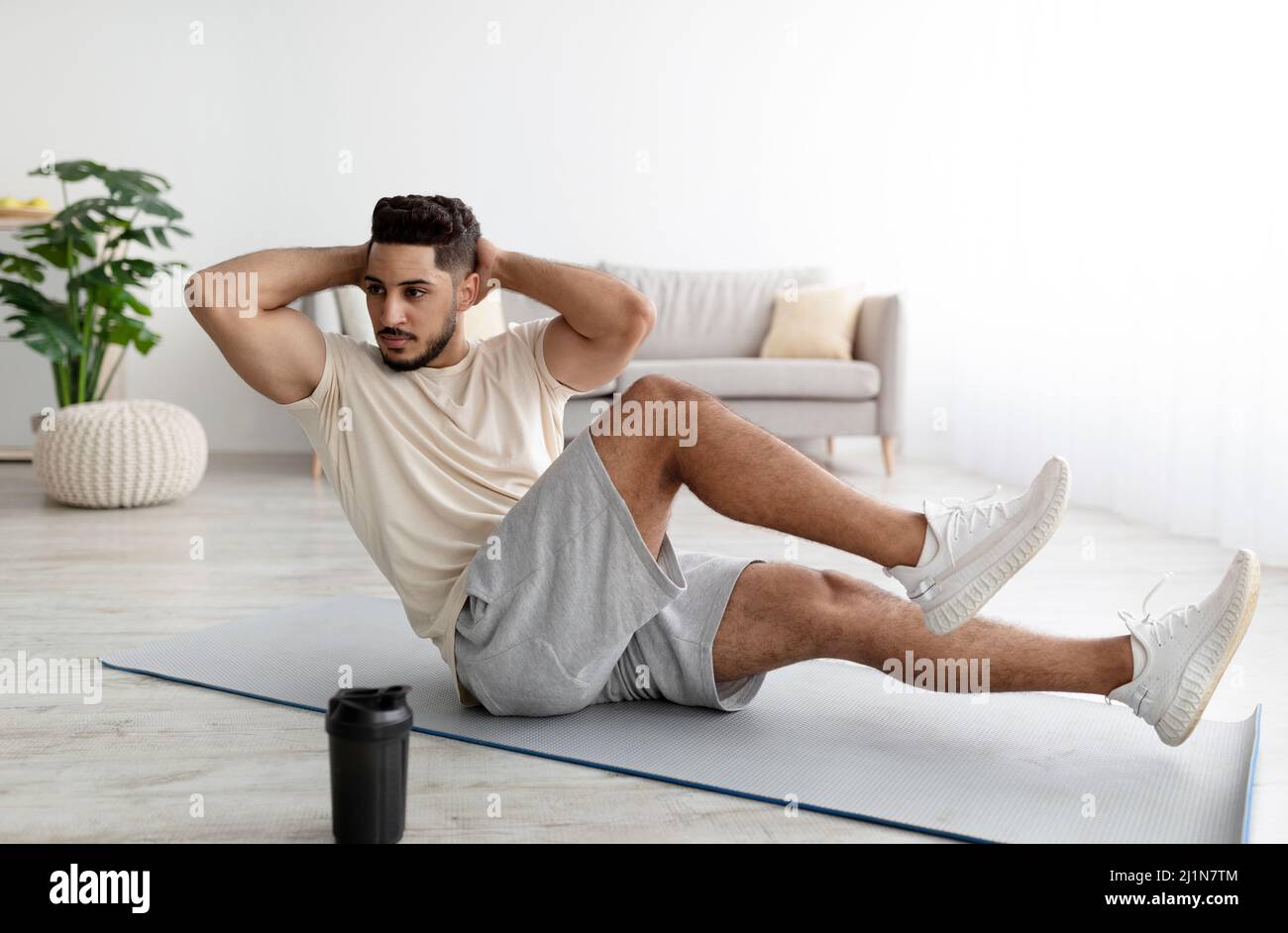 Strong young Arab man in sportswear doing exercises on yoga mat ...