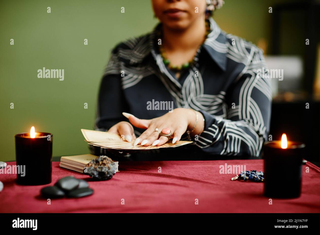 Close up of black woman reading tarot cards in fortune tellers shop lit ...