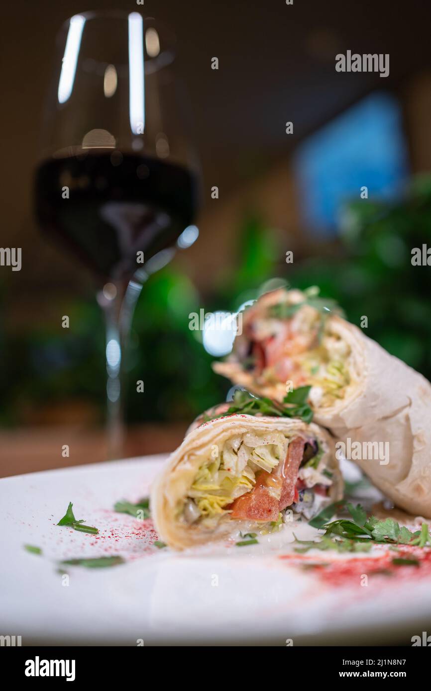 pita roll with chicken, tomato and cheese on white plate with sauce and ...