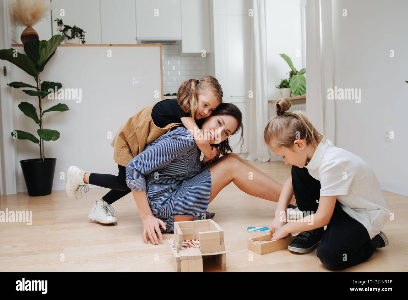 Friendly family playing on the floor. Mom and two children. Building ...