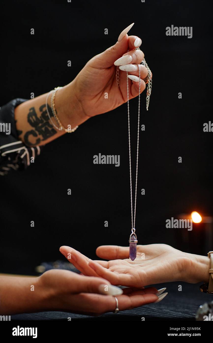 Side view close up of fortune teller holding magic crystal over hand of ...