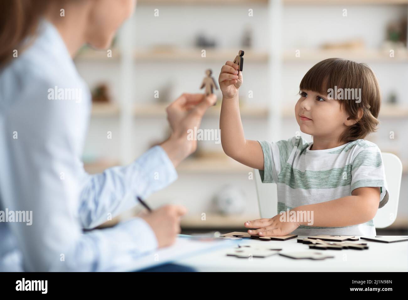 Little boy with communication problems playing with wooden figures with ...