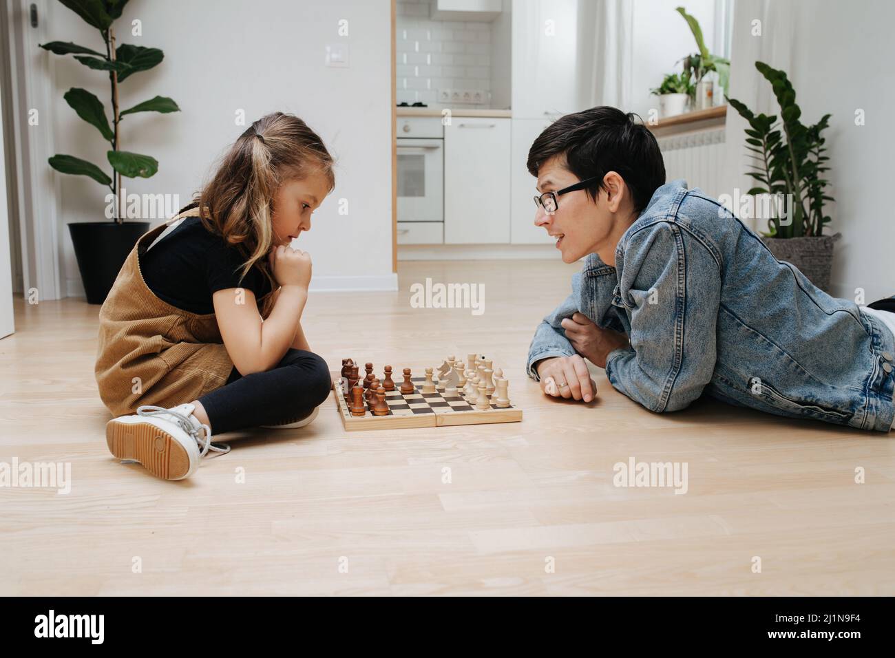 Supportive dad teaching chess to his child daughter, they play on the ...