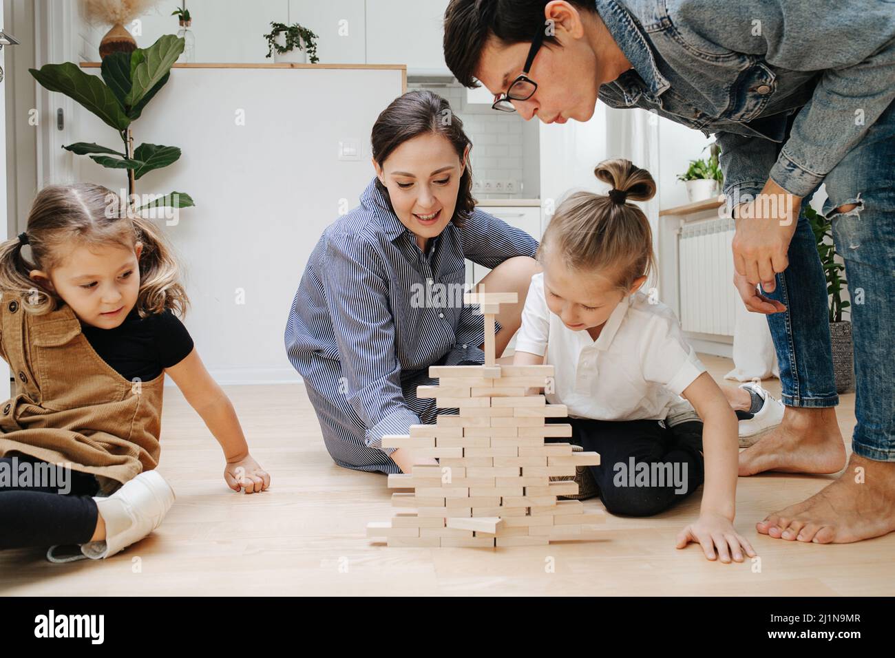 Tricky Dad Blowing On Jenga Wall While His Son Pulling A Tile Out Of