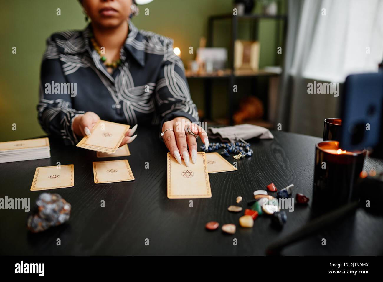 Female fortune teller doing tarot reading at table with candles during ...