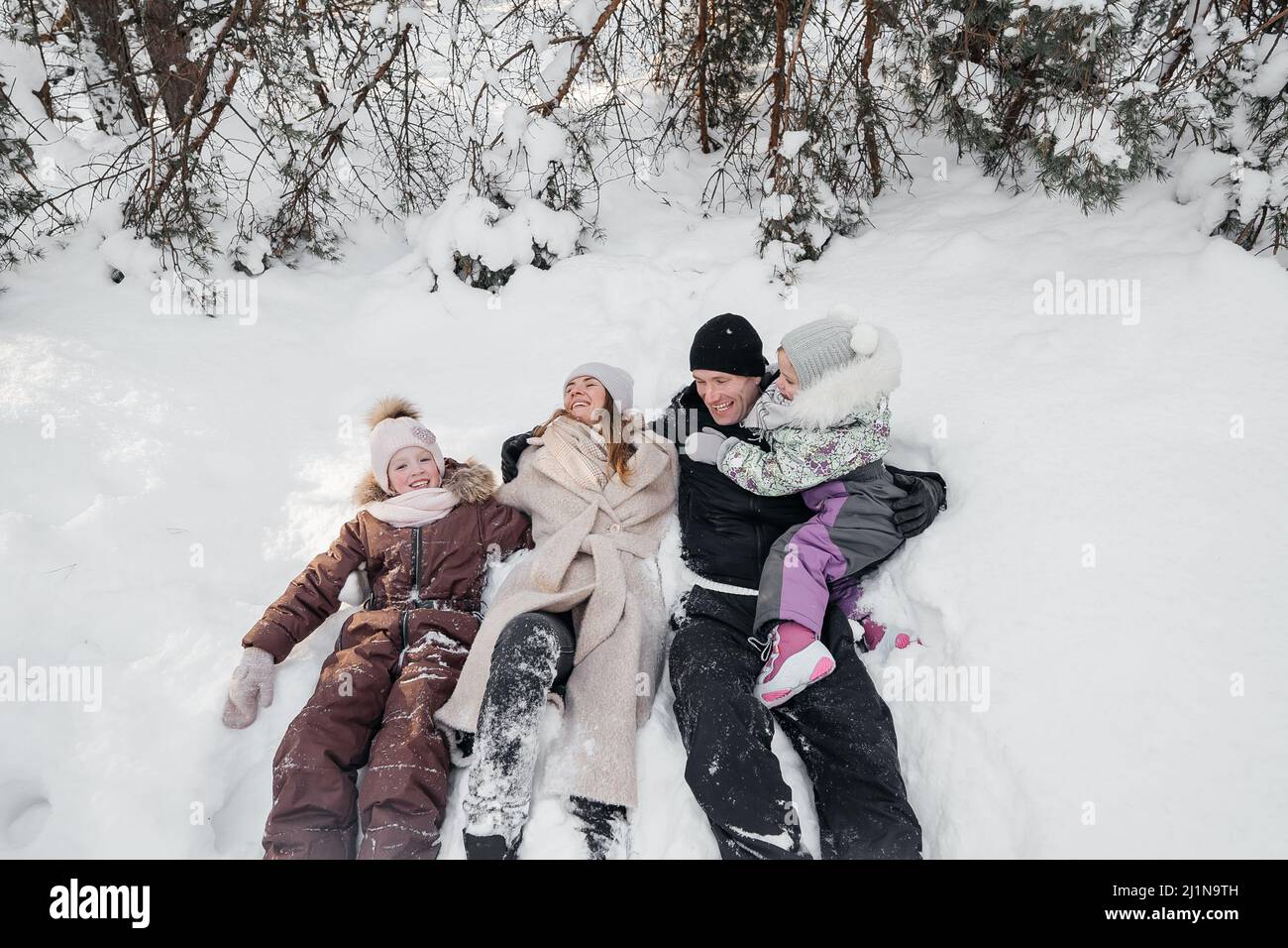 dad and mom and daughters lying in the snow in the winter forest Stock ...