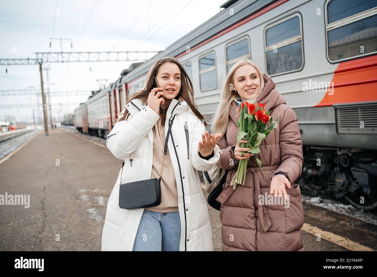 Two girlfriends meet a friend at the railway station Stock Photo - Alamy