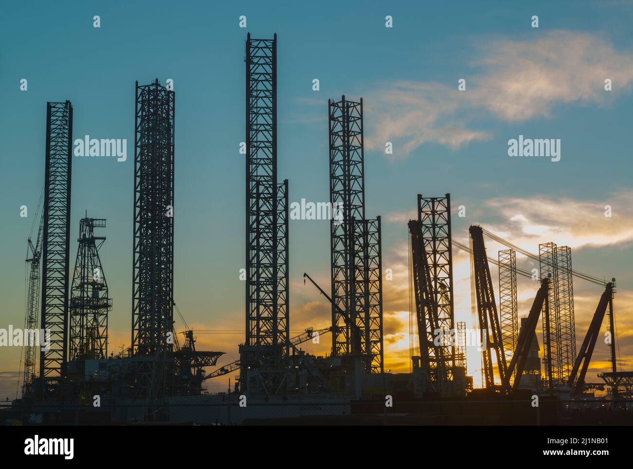 Silhouettes of disused oil rigs ready for recycling at sunset in the ...