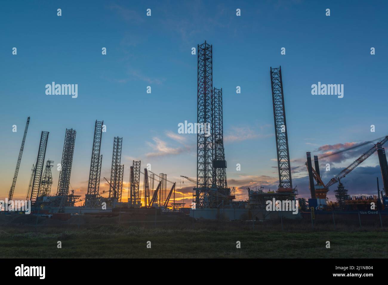 Silhouettes of disused oil rigs ready for recycling at sunset in the ...