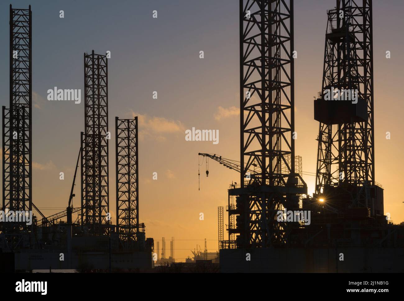 Silhouettes of disused oil rigs ready for recycling at sunset in the ...