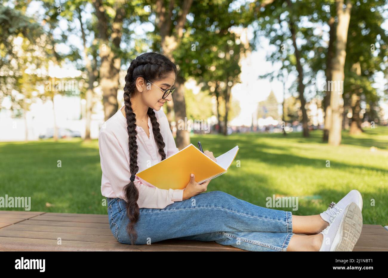 Cute indian female student writing in notebook outdoors, studying ...