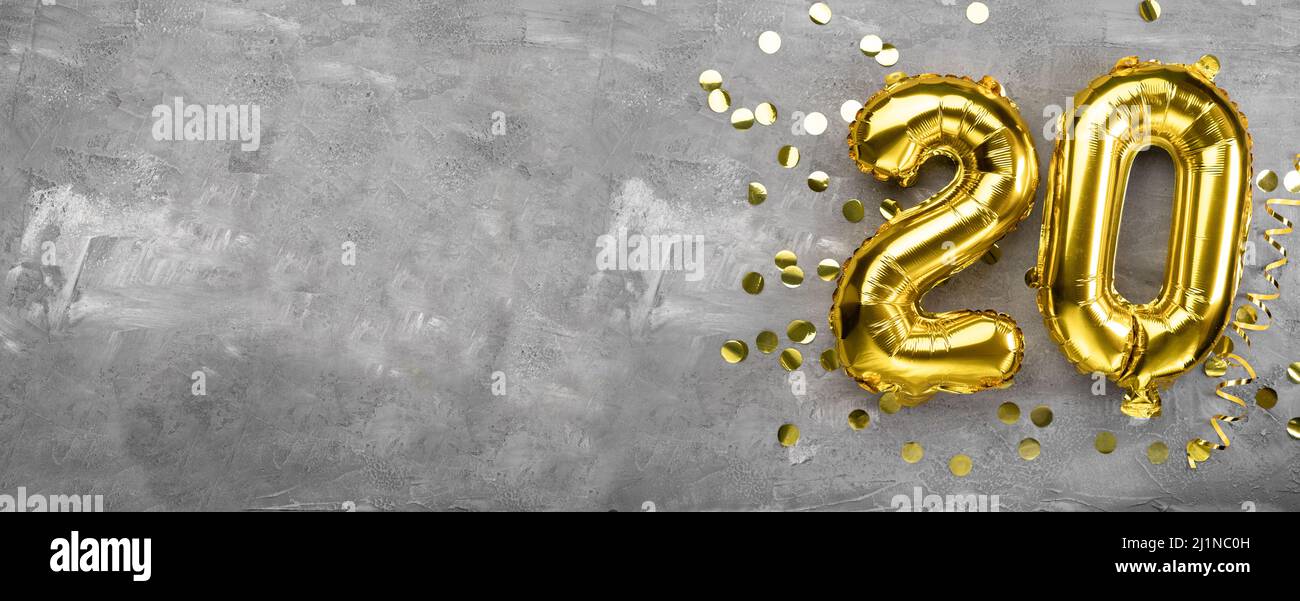Yellow foil balloon number, number twenty on a concrete background ...