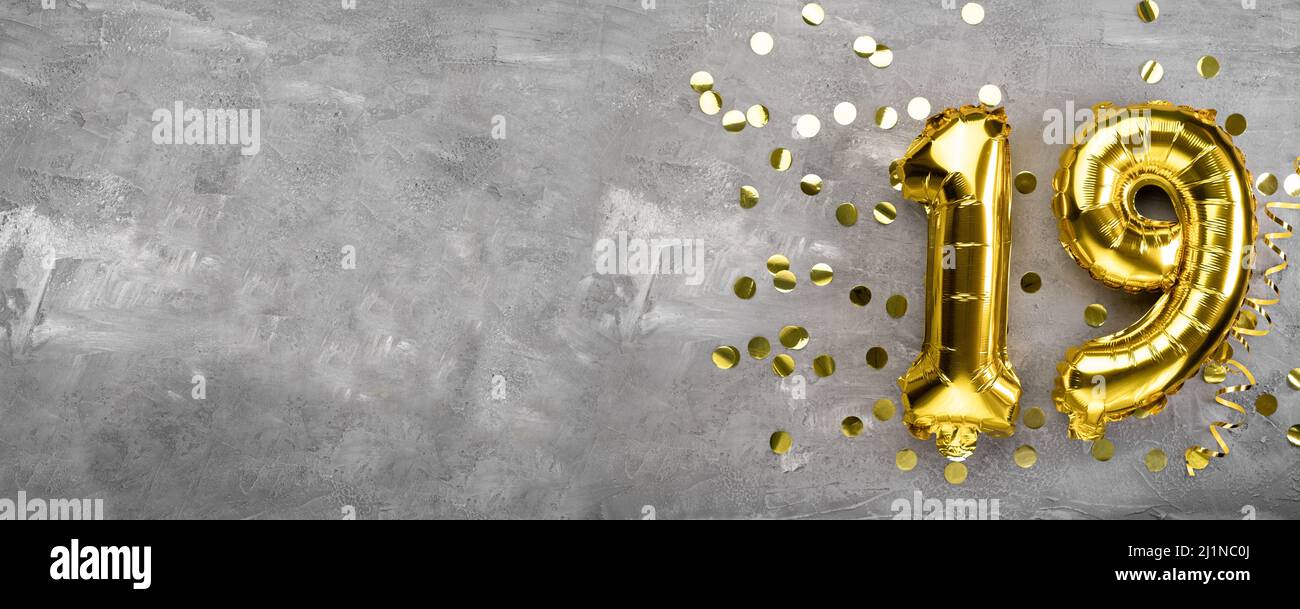 Yellow foil balloon number, number nineteen on a concrete background ...