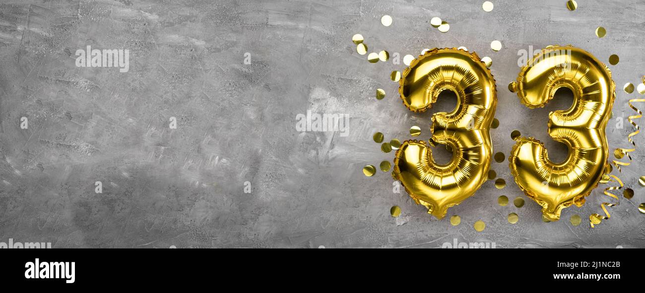 Yellow foil balloon number, number thirty three on a concrete ...