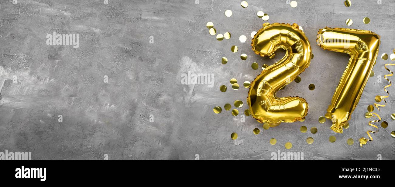 Yellow foil balloon number, number twenty-seven on a concrete ...