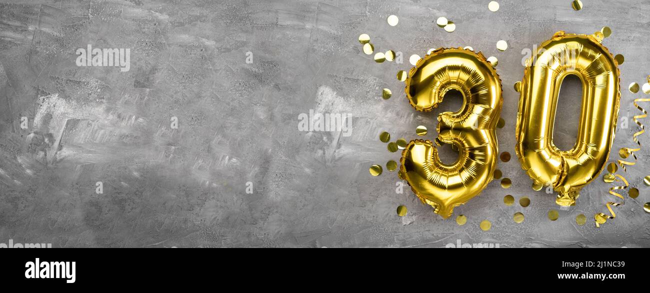 Yellow foil balloon number, number thirty on a concrete background ...