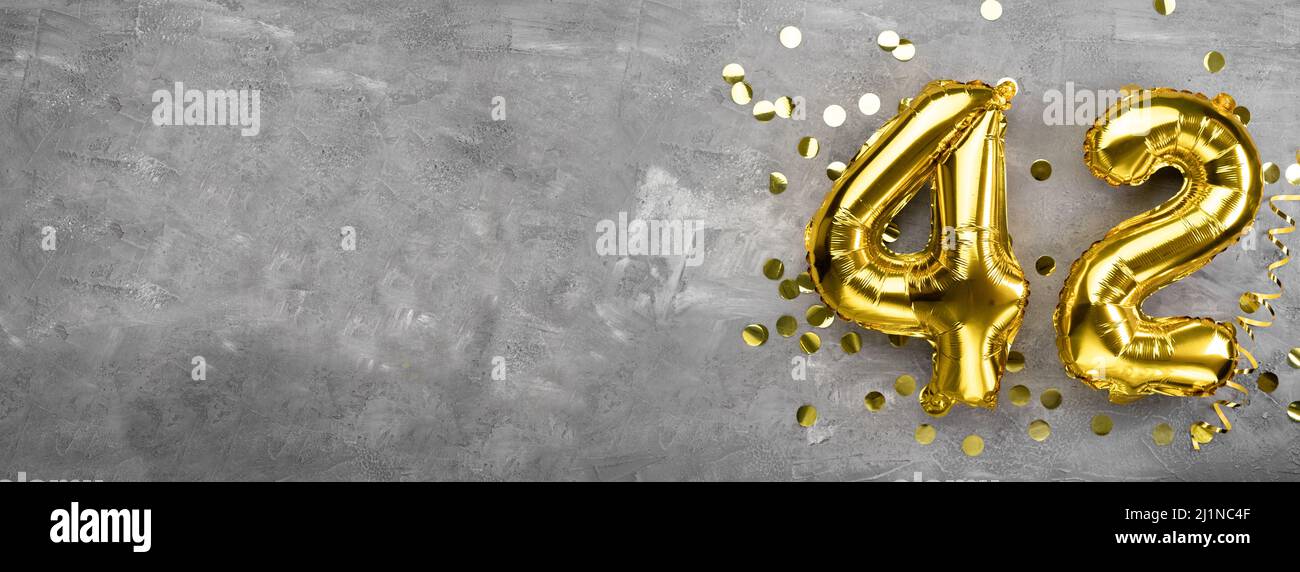 Yellow foil balloon number, number forty two concrete background ...